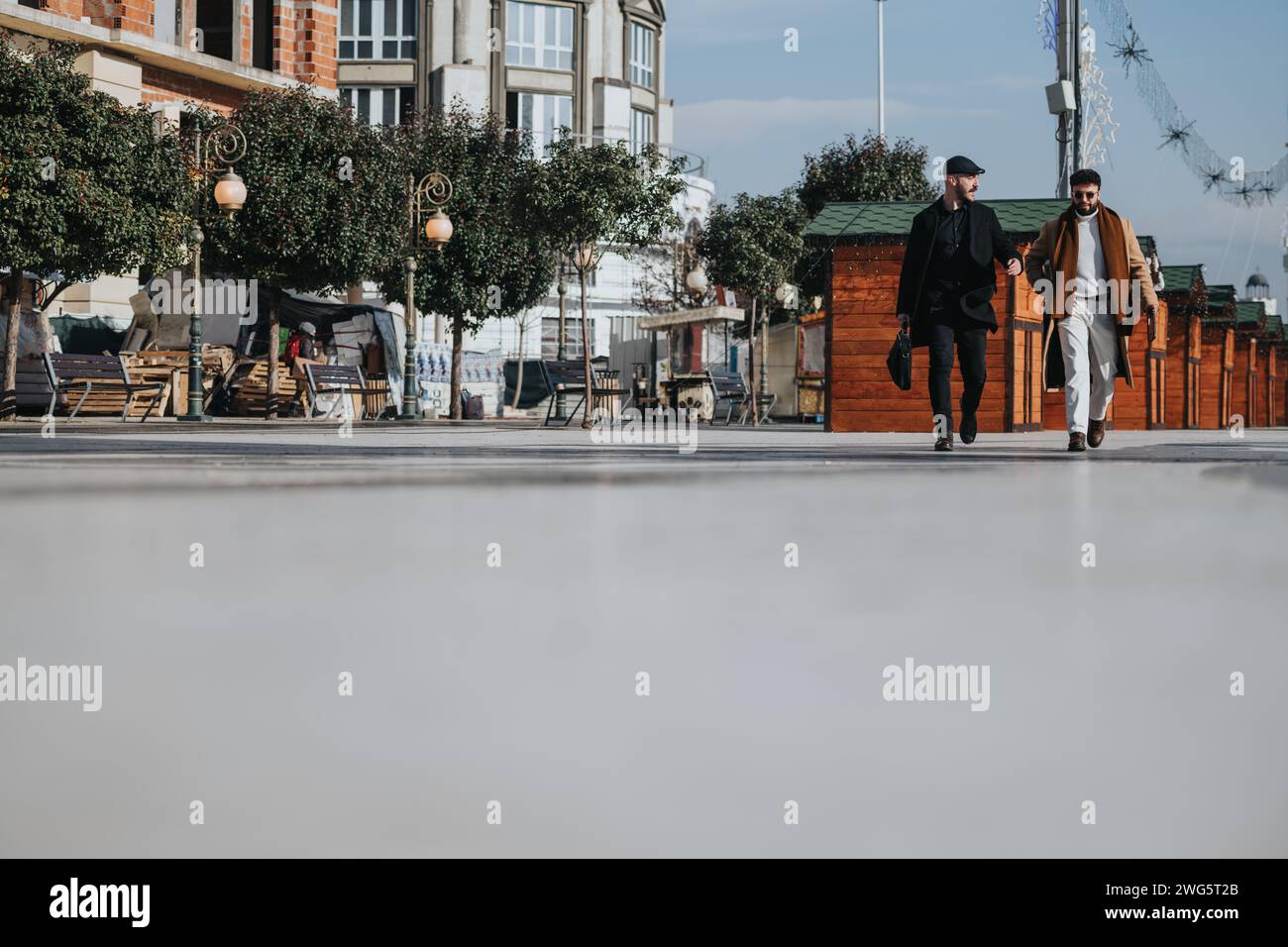 Two fashionable men walking together in an urban setting during daytime ...