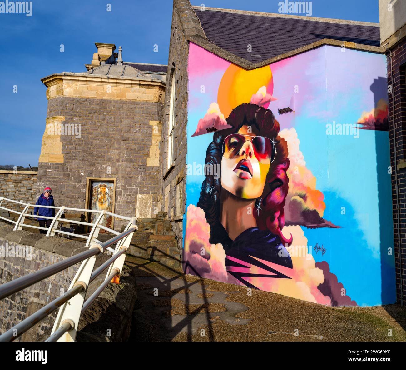Mural of a woman in dark glasses enjoying the sunshine on the wall of a ...