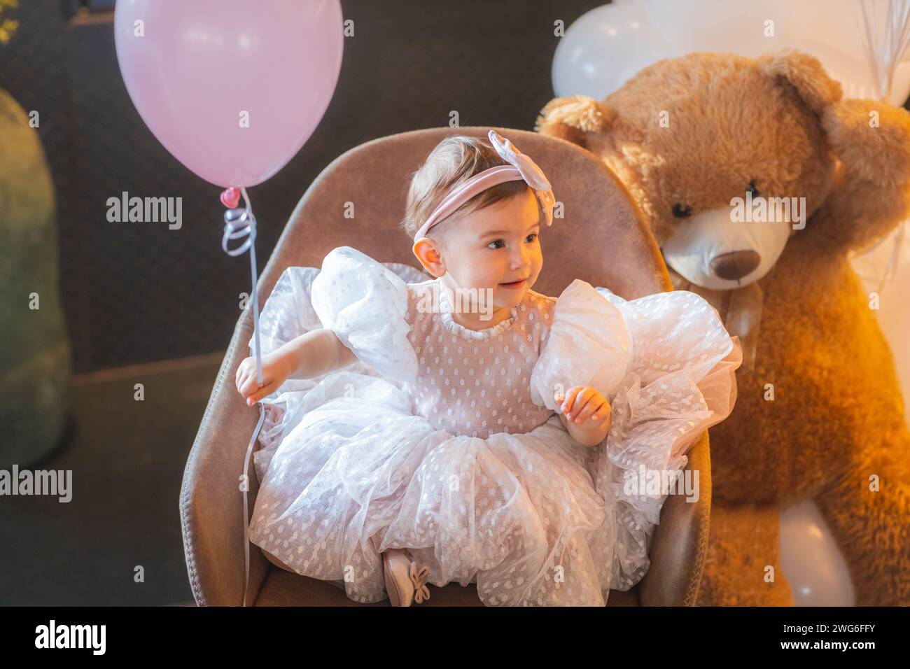 Portrait of a beautiful one year old baby girl in her birthday dress ...