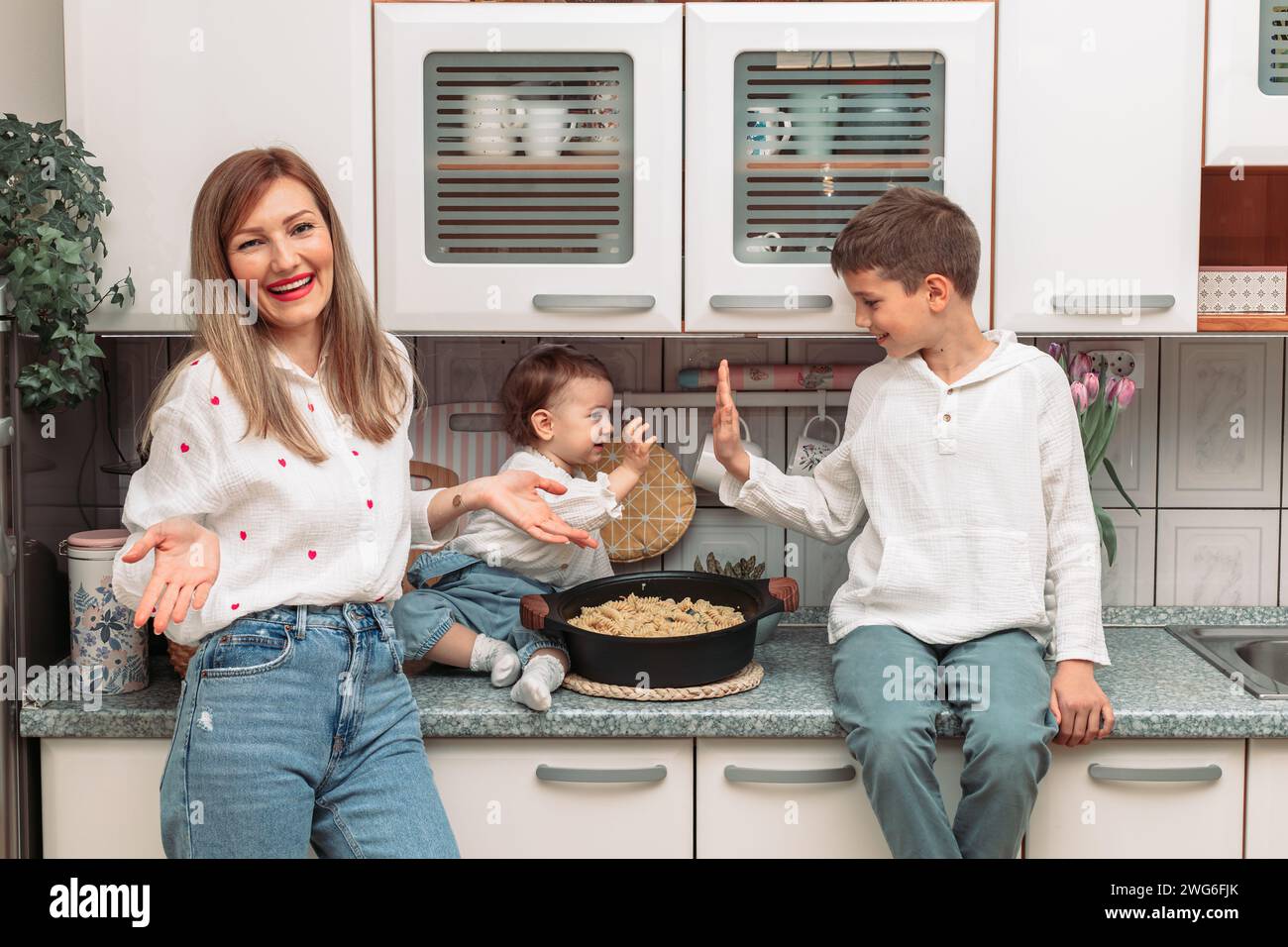 Mom and her children in the kitchen with pasta in the pan for dinner ...
