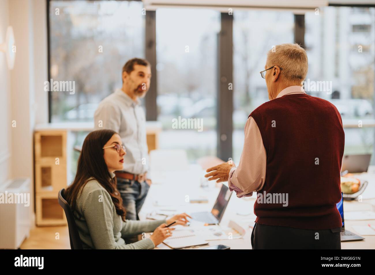 Three colleagues collaborate and share ideas at a brightly lit office ...