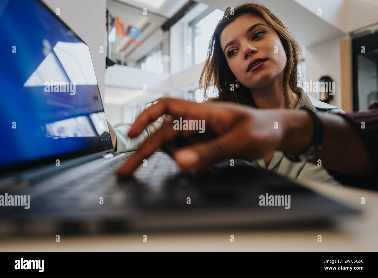 Close-up of a concentrated female employee using a laptop at her ...