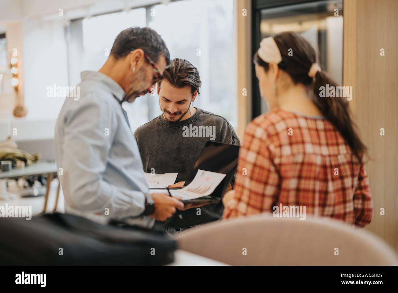 Multi generational, business colleagues collaborating on project in ...