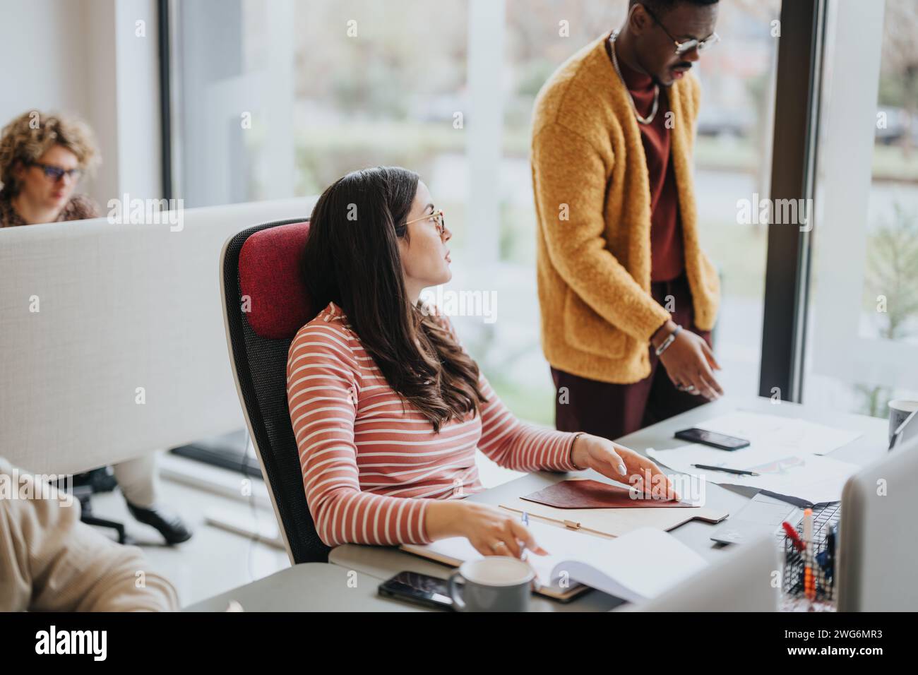 Focused team members collaborating in a well-lit office environment ...