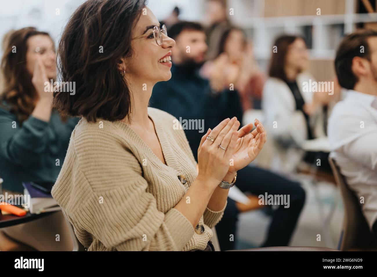 Woman in a beige sweater joyfully clapping her hands, expressing ...