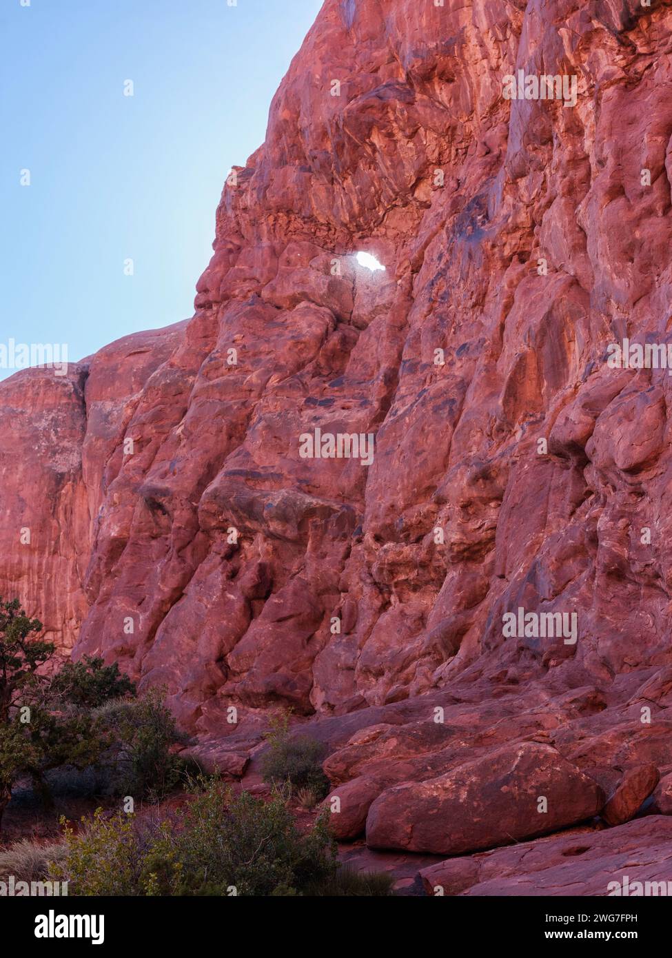 United States. Utah. Arches National Park. The sun peeps out from a ...