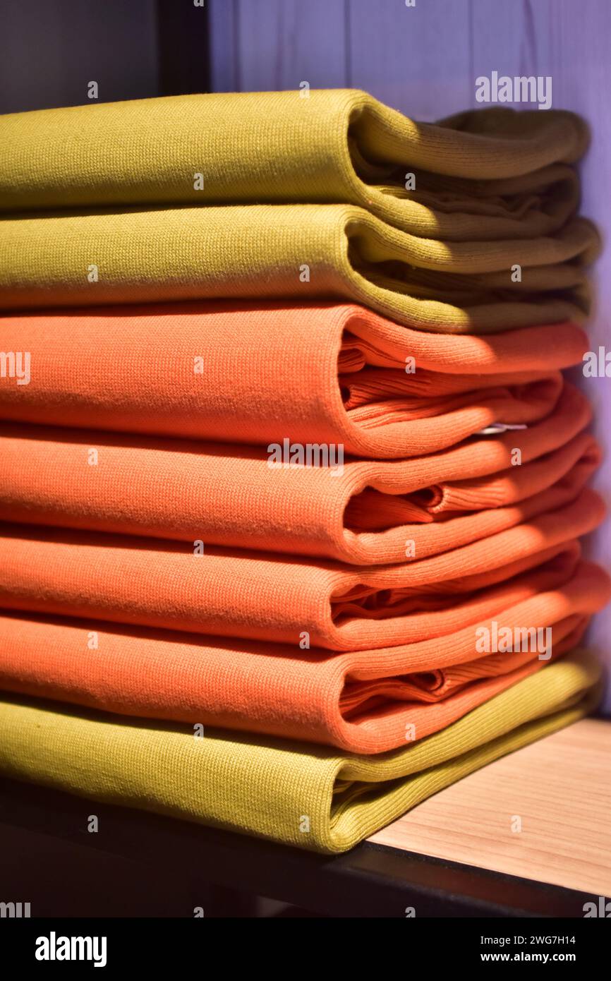 Stack of colorful clothes in a boutique. Merchendising clothing store ...