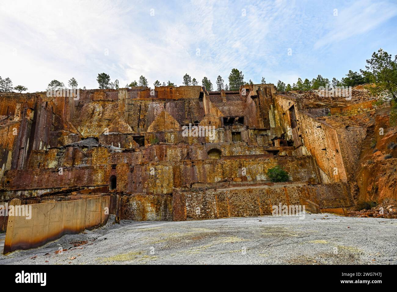 Decaying remains of mining structures stand over a stagnant water body ...