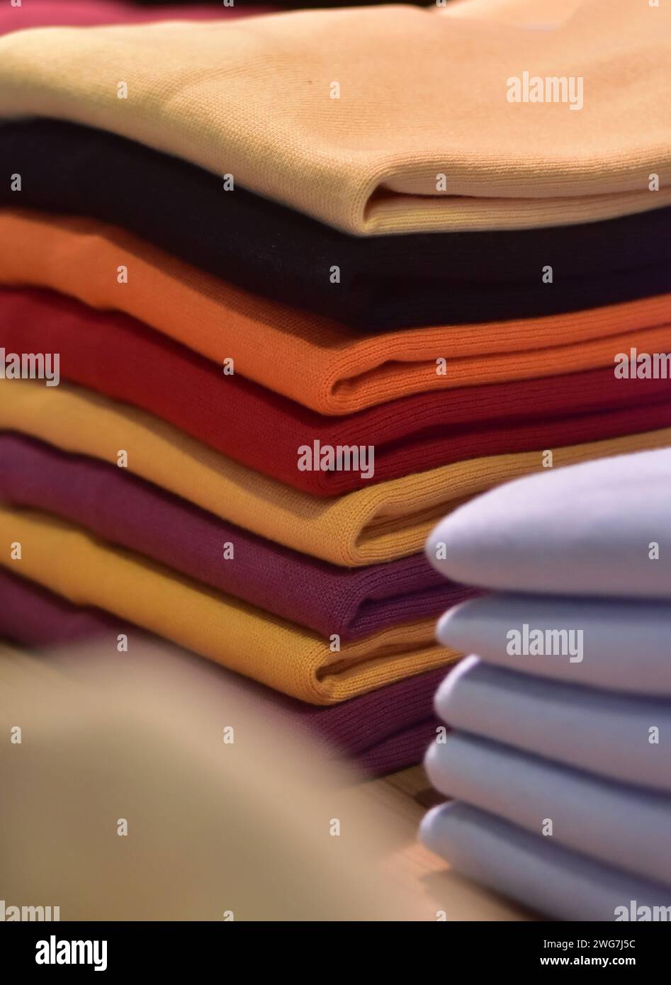 Stack of colorful clothes in a boutique. Merchendising clothing store ...