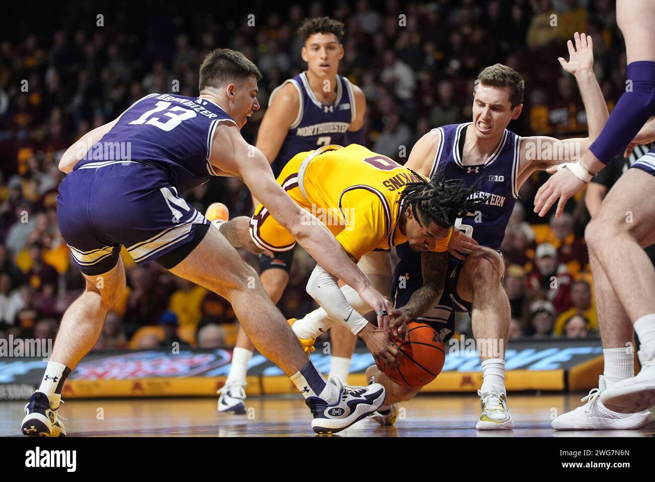 Minnesota guard Elijah Hawkins, center, loses control of the ball ...