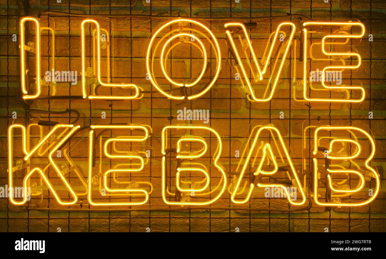 Neon shining sign in yellow warm color on a brick wall with the ...