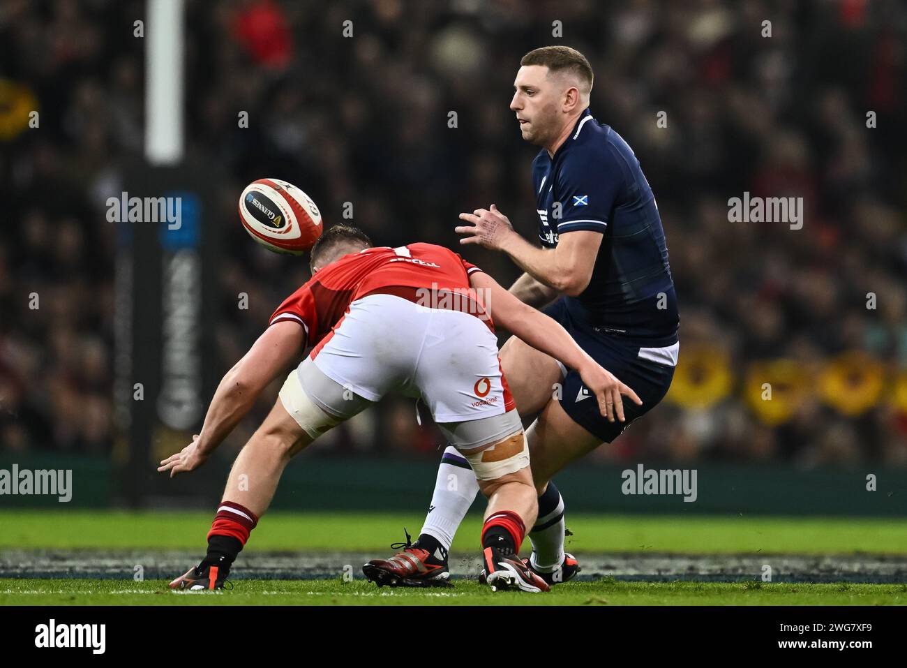 Finn Russell of Scotland offloads the ball before the tackle of Tommy ...