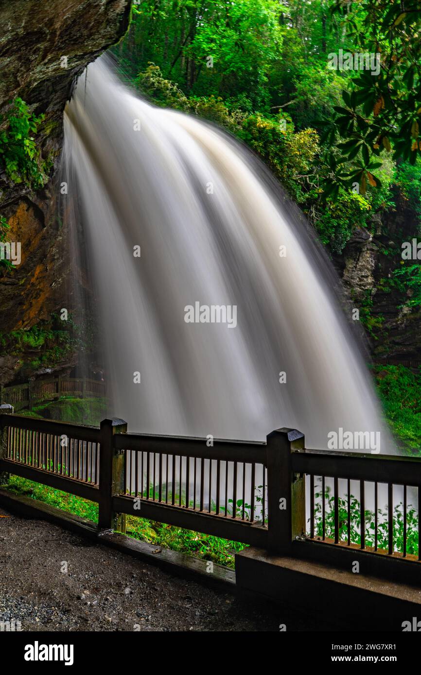 Waterfall cascading by a rocky fence amidst lush trees Stock Photo - Alamy