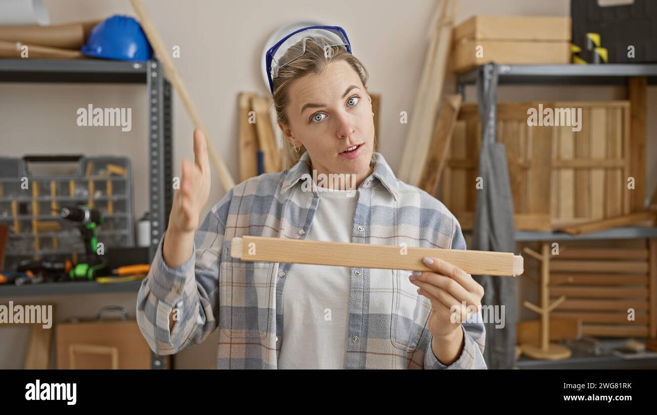 A young woman wearing safety glasses holds lumber with a surprised ...
