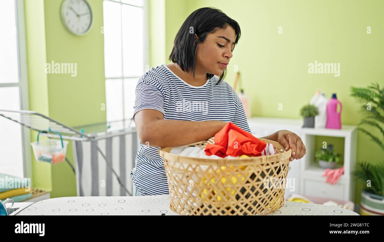 Hispanic woman sorting laundry in a bright, green home interior ...