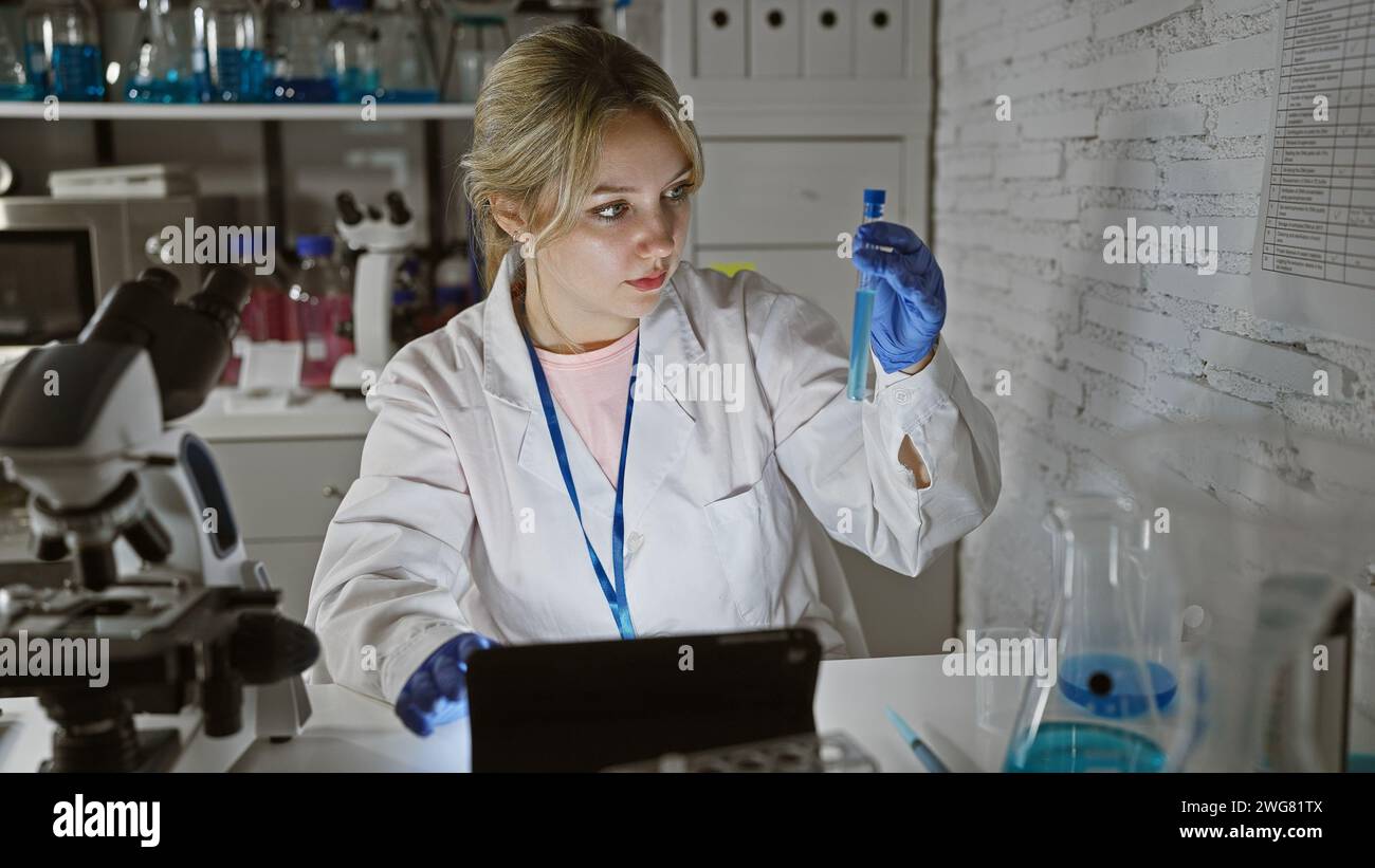 A young blonde woman in a lab coat examines a test tube in a well ...