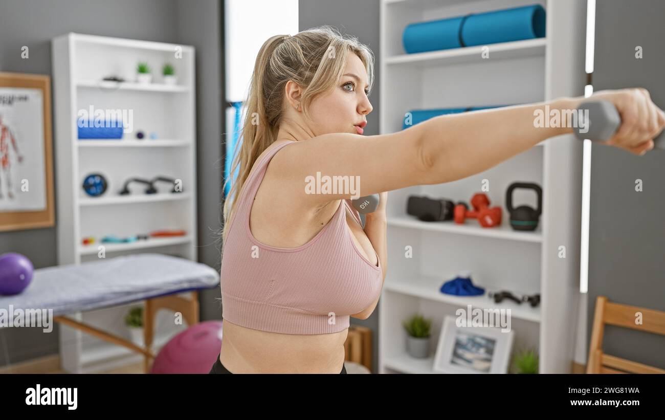 A focused young woman exercises with a dumbbell in a well-equipped ...