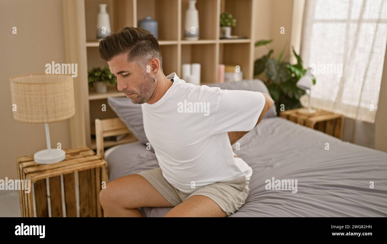 Worried, young hispanic man suffering from an agonizing back injury ...