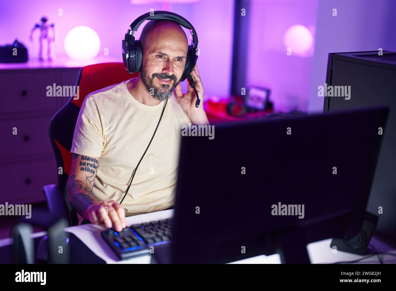 Young bald man streamer playing video game using computer at gaming ...