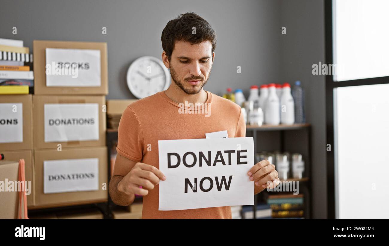 Hispanic man holding a 'donate now' sign in a warehouse filled with ...