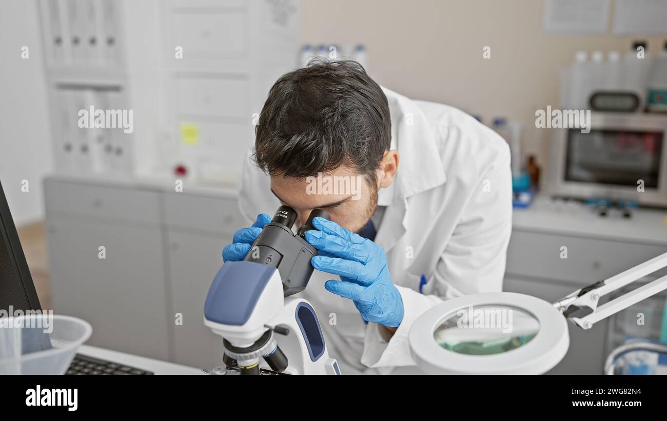 Hispanic man using microscope in laboratory setting, reflecting ...