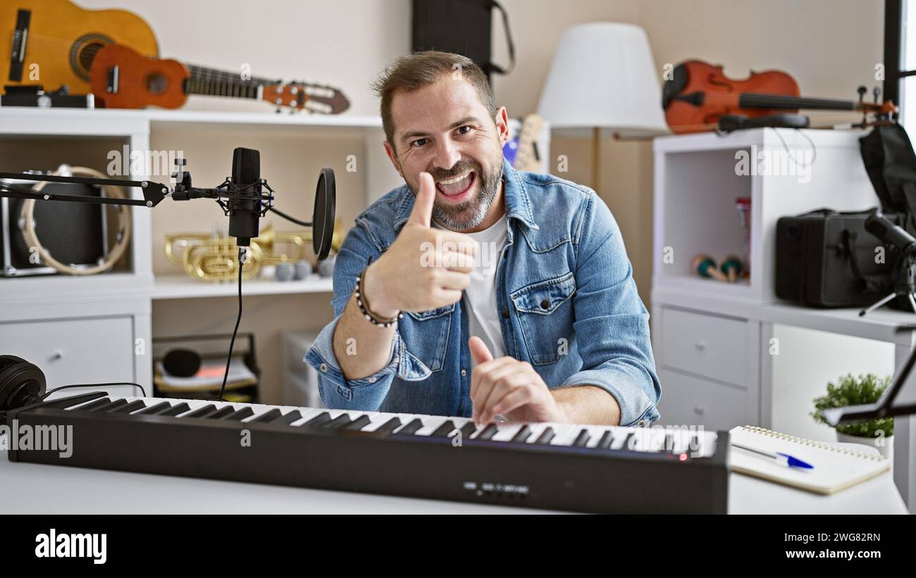 Handsome mature hispanic man giving a thumbs-up in a music studio with ...