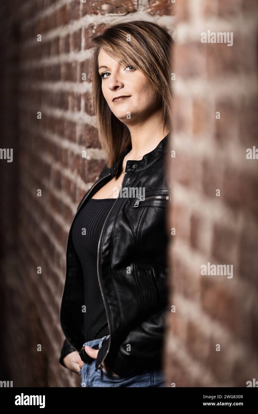 Young woman in portrait in urban location, brick wall building ...