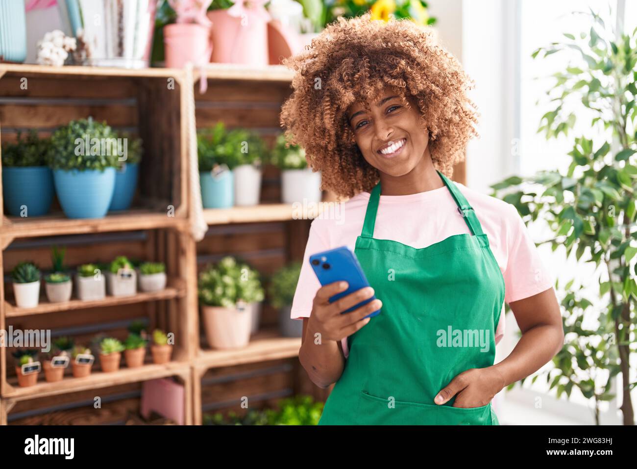 African american woman florist smiling confident using smartphone at ...