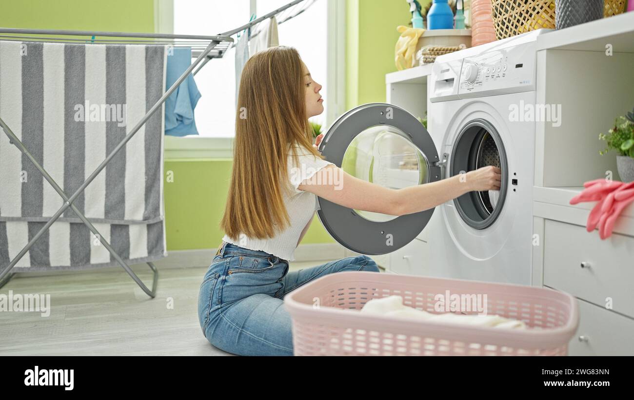 Young blonde woman washing clothes at laundry room Stock Photo - Alamy