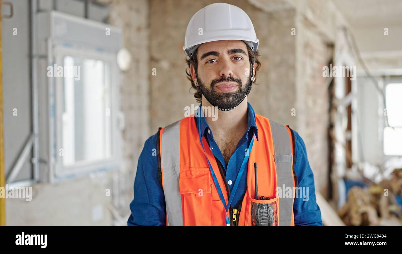 Young hispanic man architect standing with serious face at construction ...