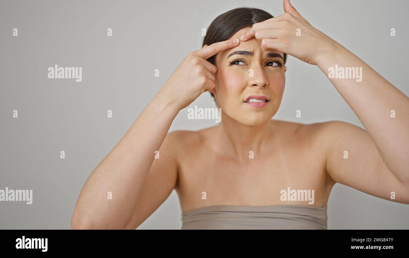 Young beautiful hispanic woman popping pimple over isolated white ...