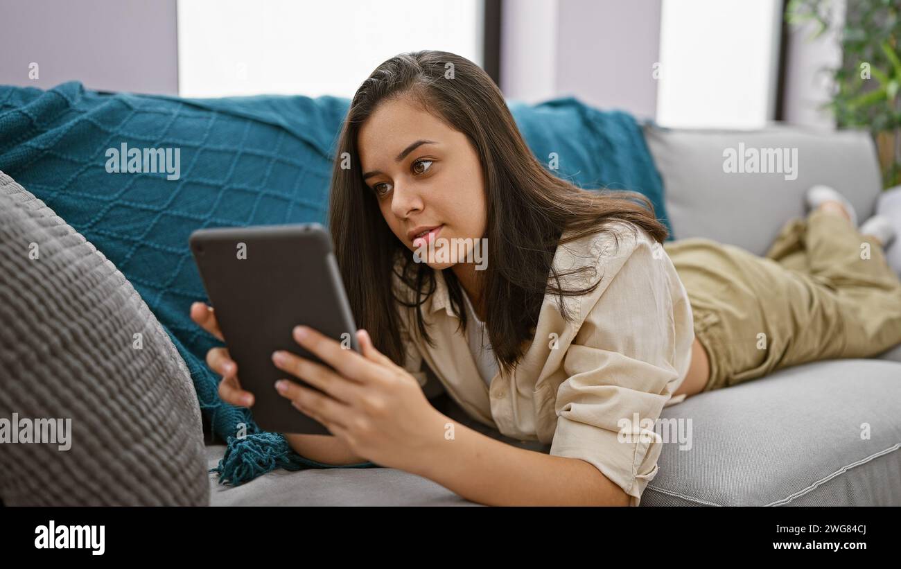 Relaxed young hispanic woman enjoys comfort of home, lying on sofa ...