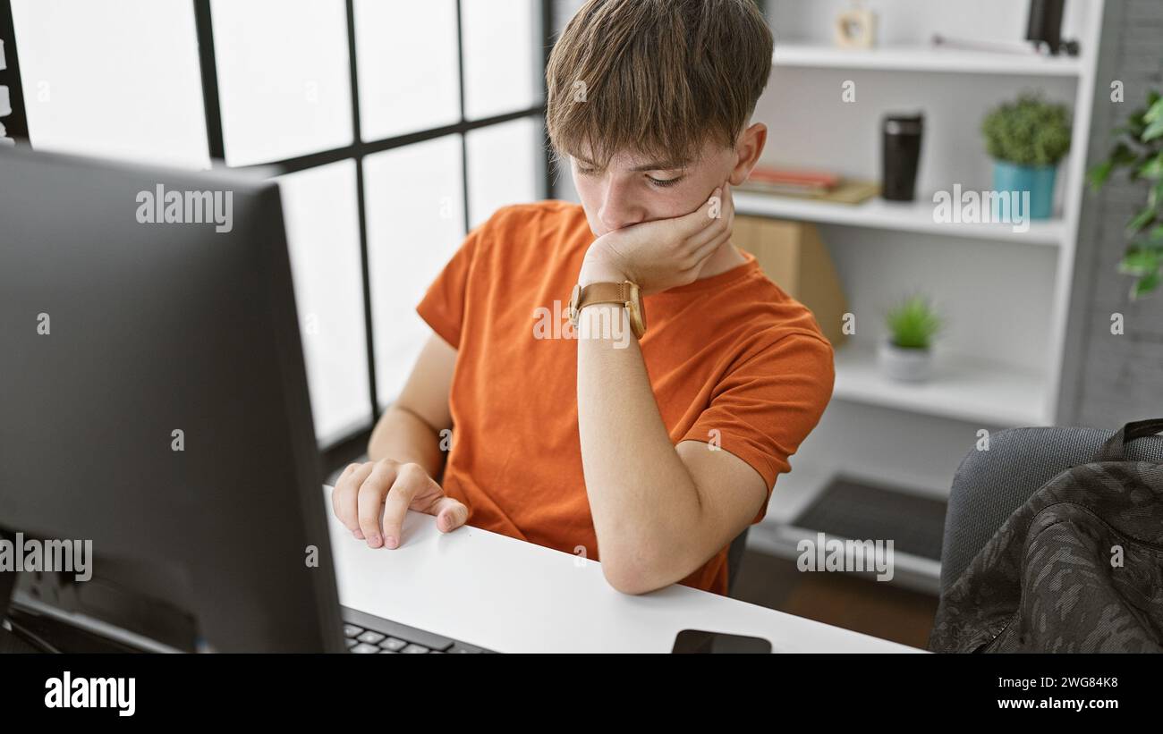 Young blond man studying on computer in modern university library ...