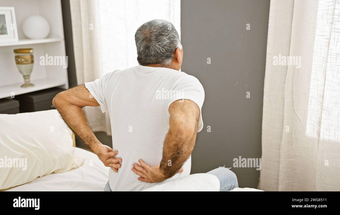 A middle-aged man with grey hair is experiencing back pain in his ...