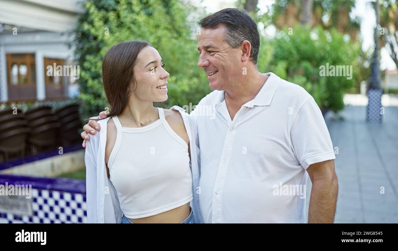 Confident father sharing sunny, joyful hug with smiling daughter at ...