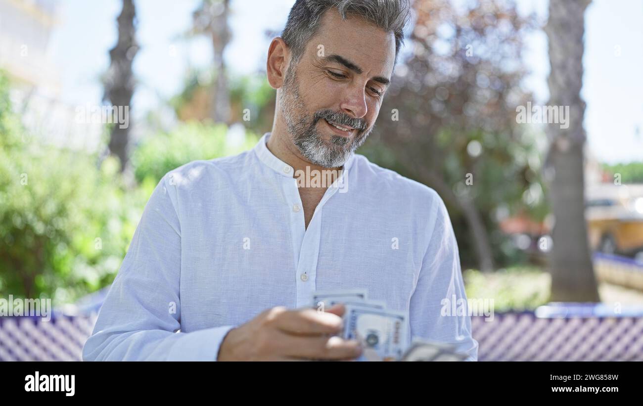 Confident young hispanic man with grey-hair casually counts dollar ...