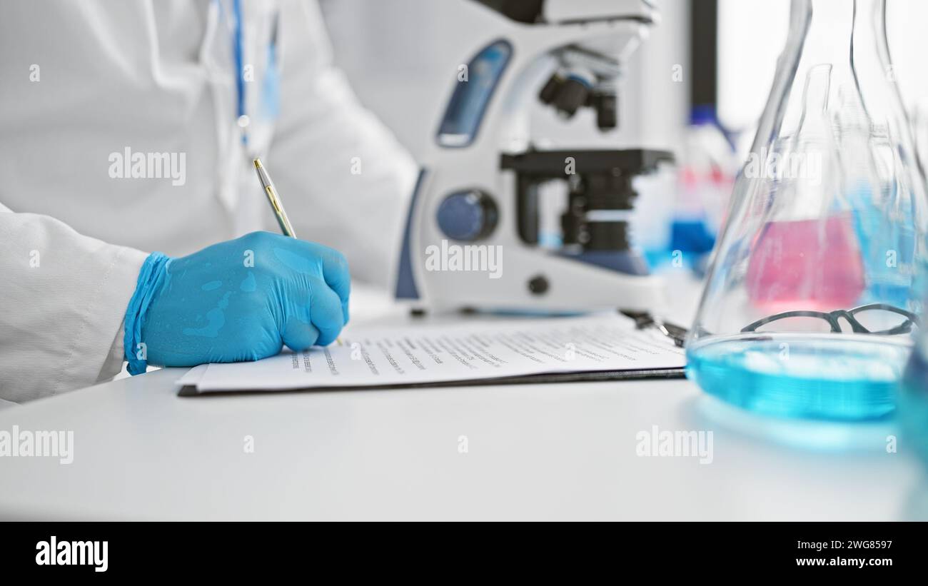 Handsome young hispanic grey-haired male scientist hulked over ...