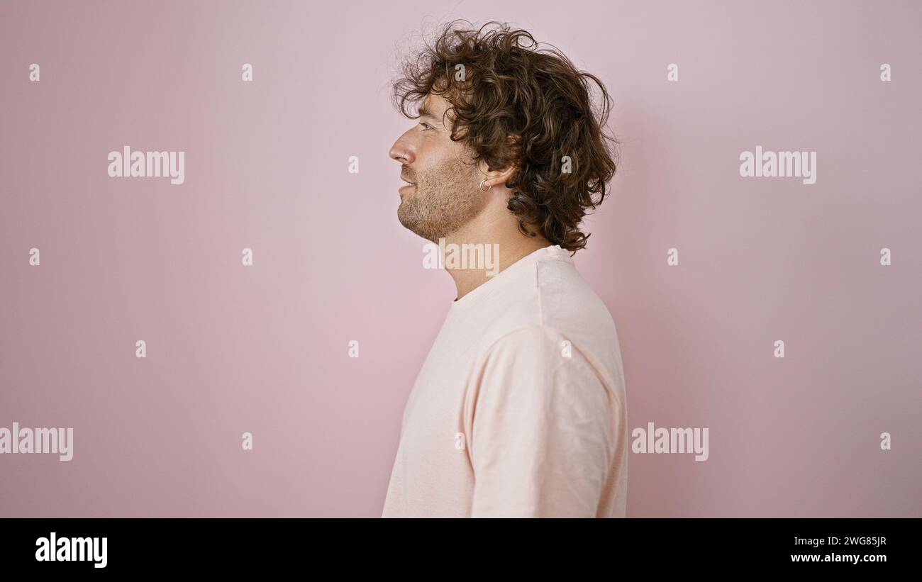 A side-profile portrait of a young, curly-haired man against a pastel ...