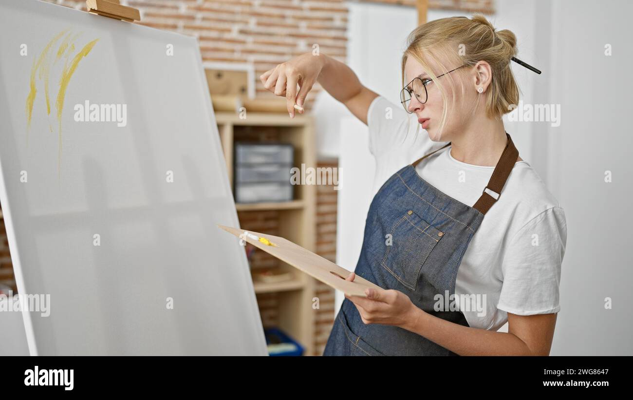 Young blonde woman artist looking draw thinking at art studio Stock ...