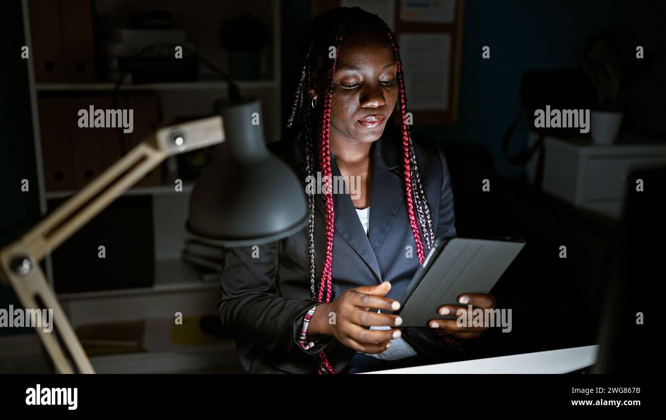 Focused african american woman worker at office, monitors aglow, braids ...