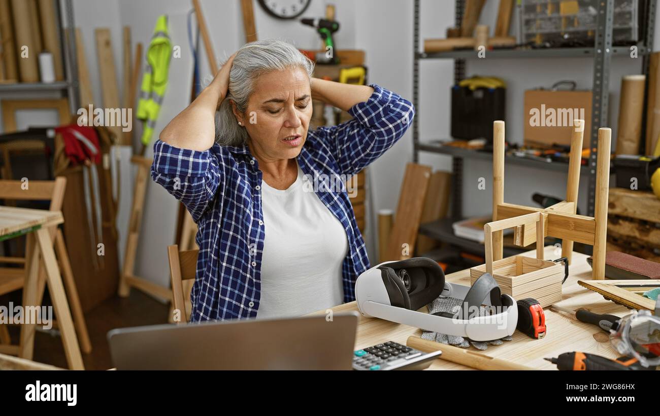 A stressed woman stands in a cluttered workshop, with woodworking tools ...
