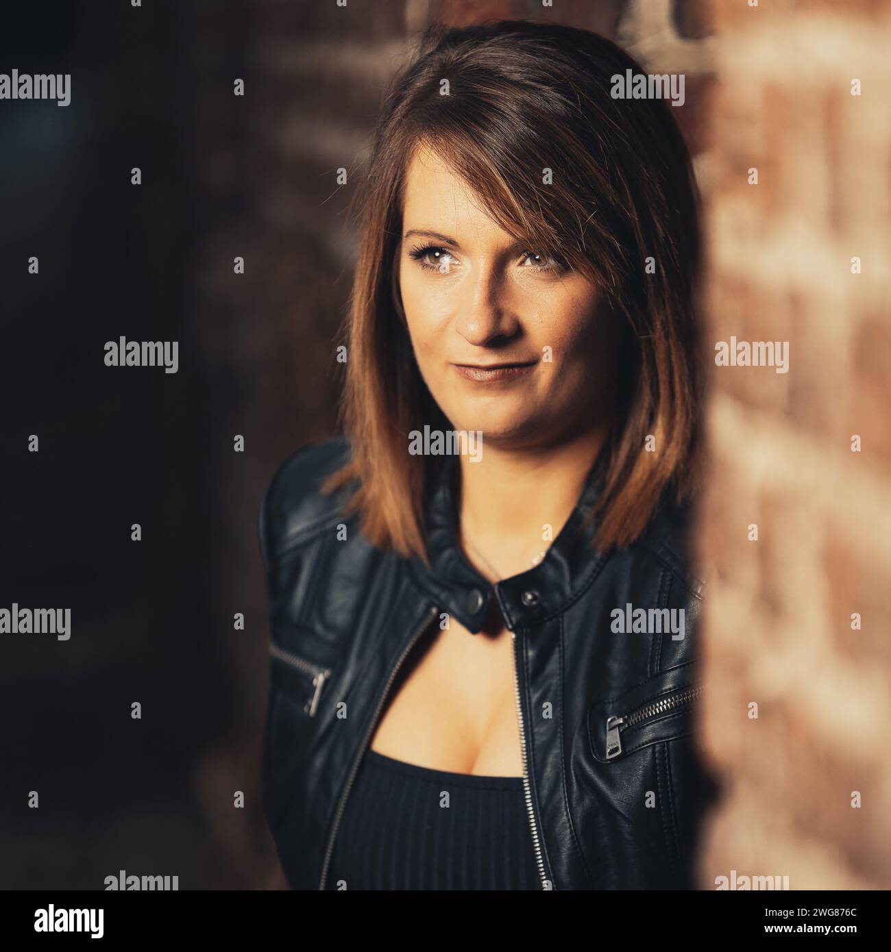 Young woman in portrait in urban location, brick wall building ...