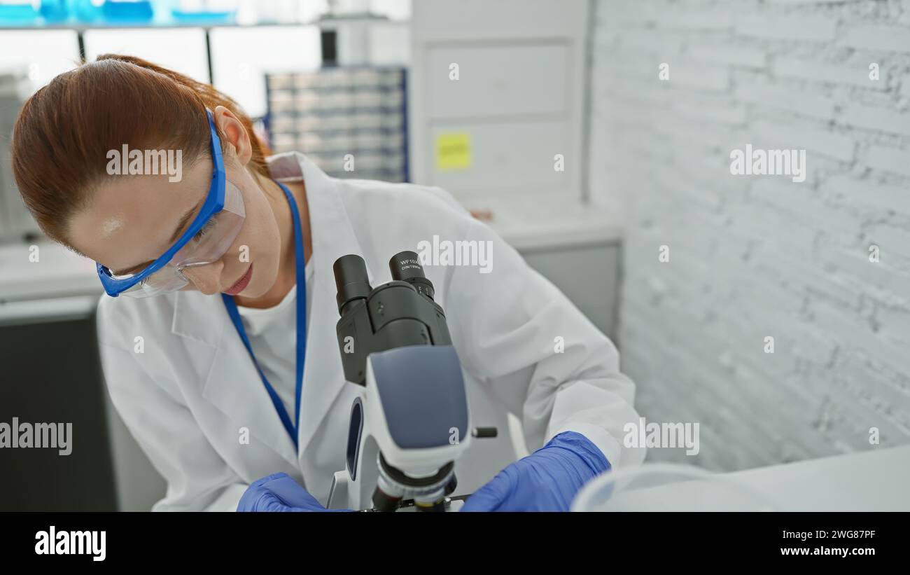 A focused caucasian woman wearing protective goggles examines a ...