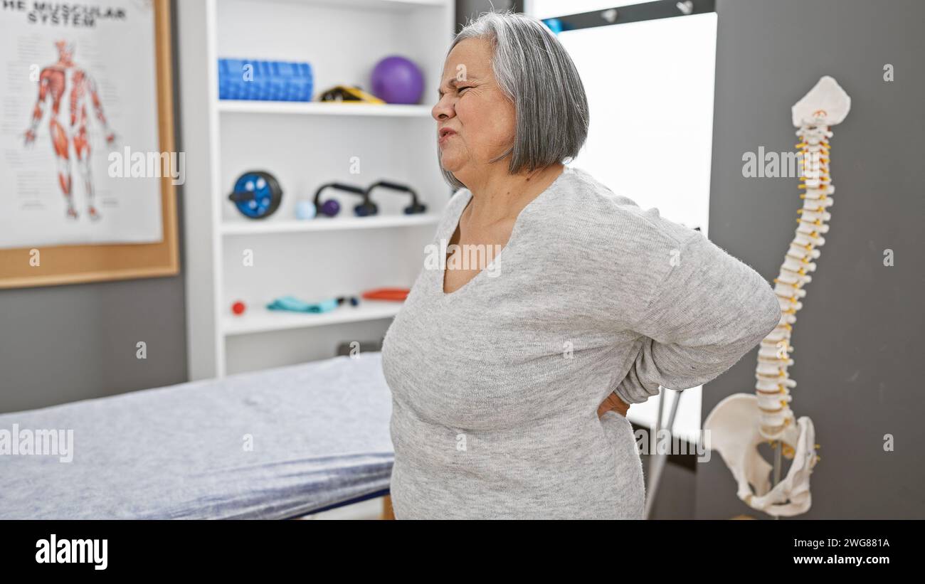 Mature woman with back pain at physiotherapy clinic standing near ...