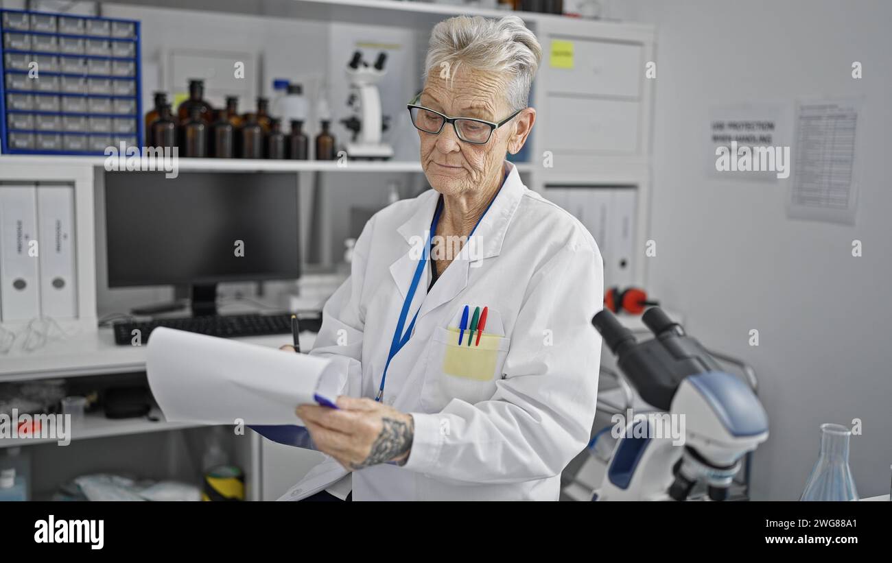 Dedicated senior grey-haired scientist woman, in lab coat, taking ...