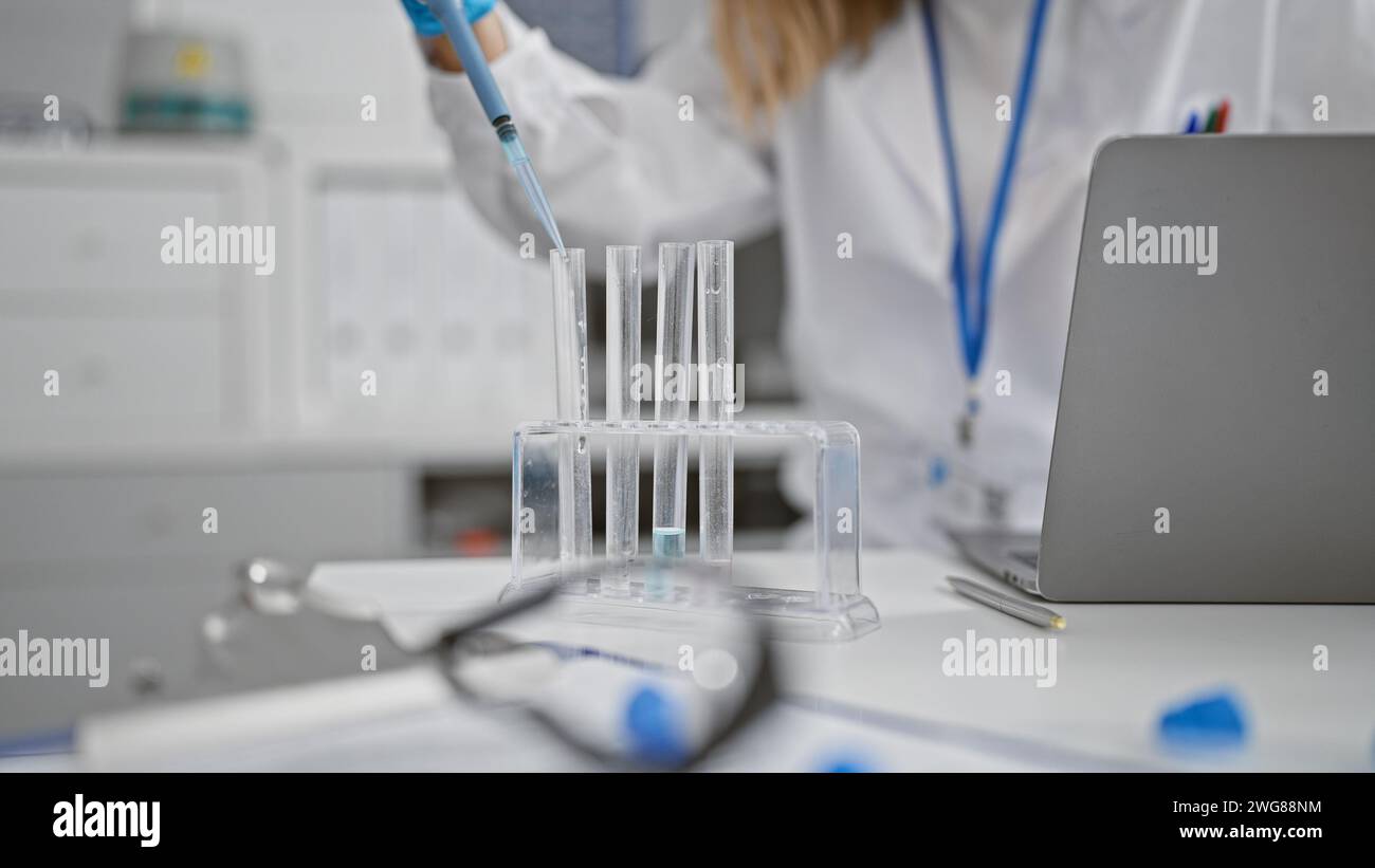 Beautiful young blonde woman scientist passionately pouring liquid into ...