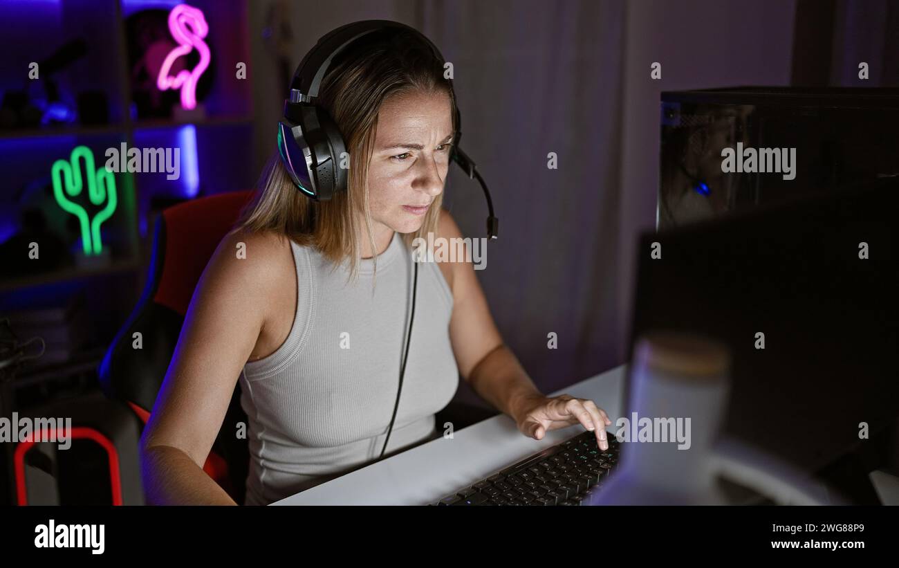 Attractive young blonde woman streamer, locked in her gaming room ...