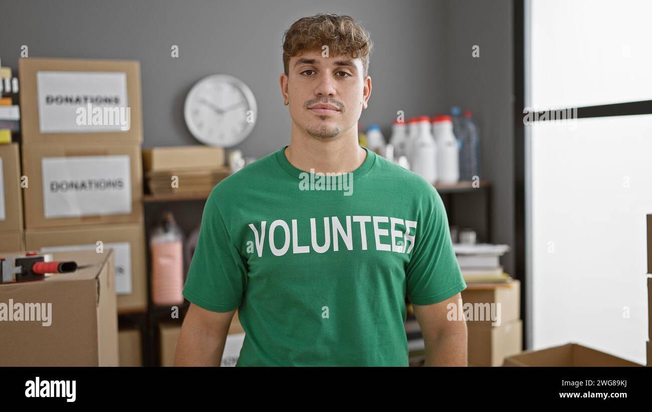Handsome young hispanic man volunteers at charity center, his serious ...