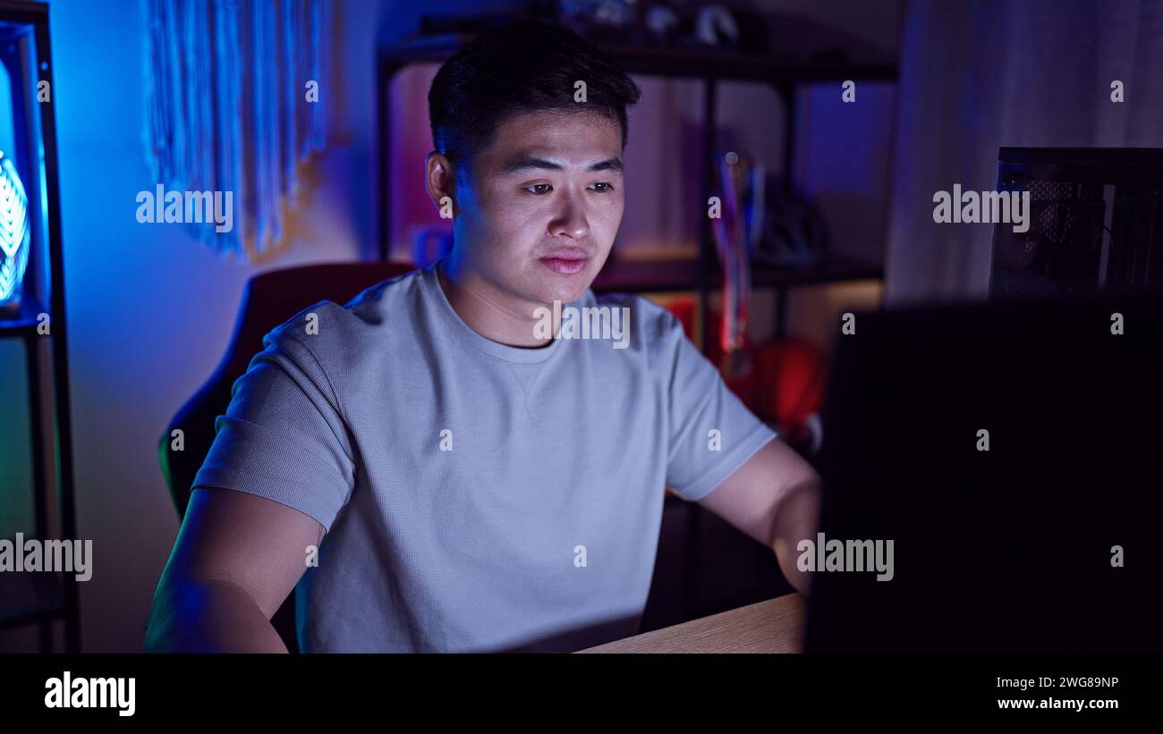 Handsome young asian man concentrating on a computer screen in a ...