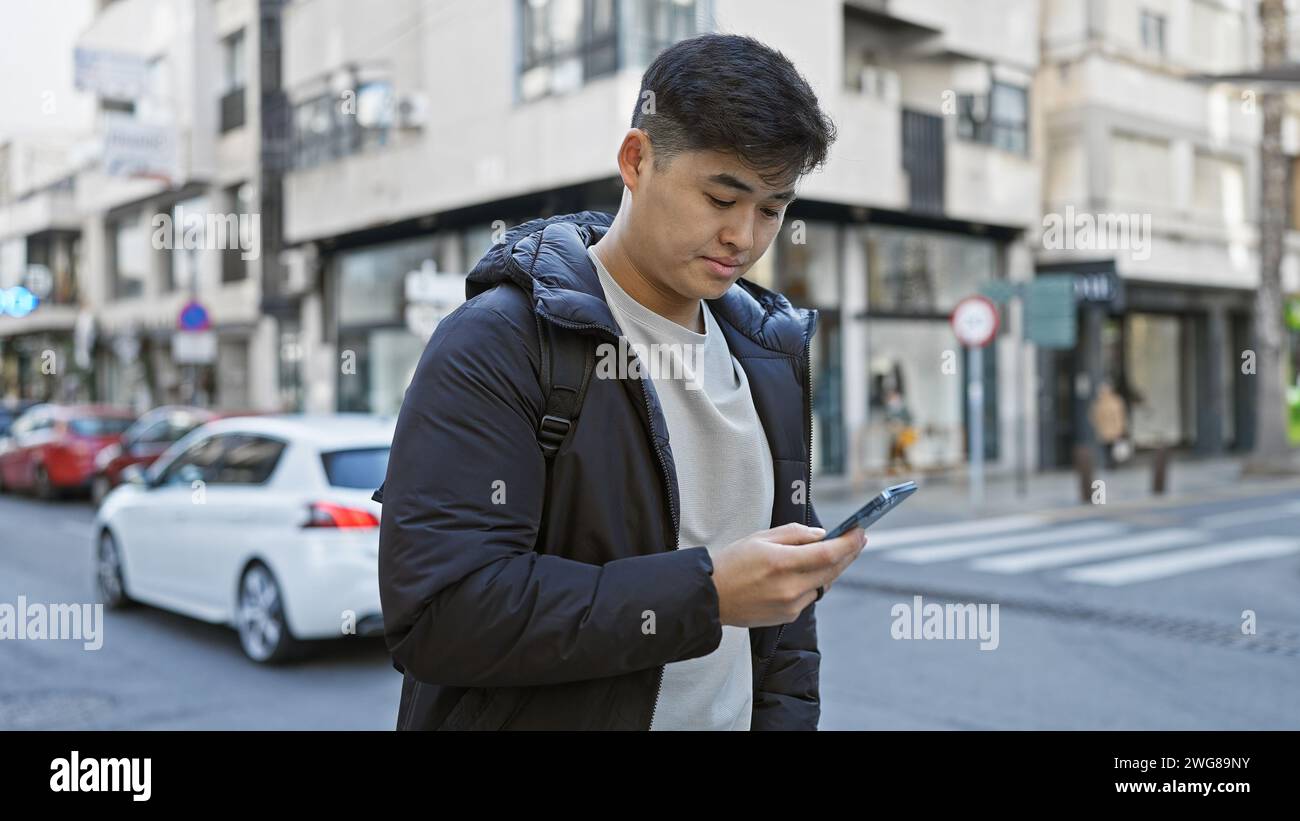 Handsome asian man using smartphone on a bustling city street ...